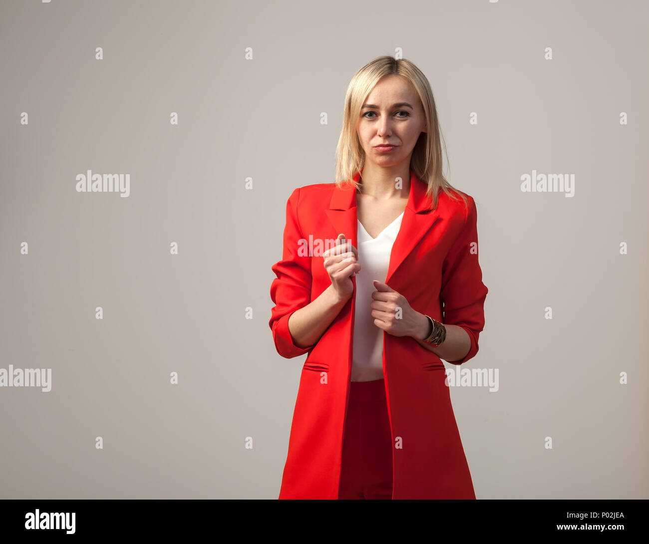 Young beautiful white blond girl in a bright red strict suit with a ...