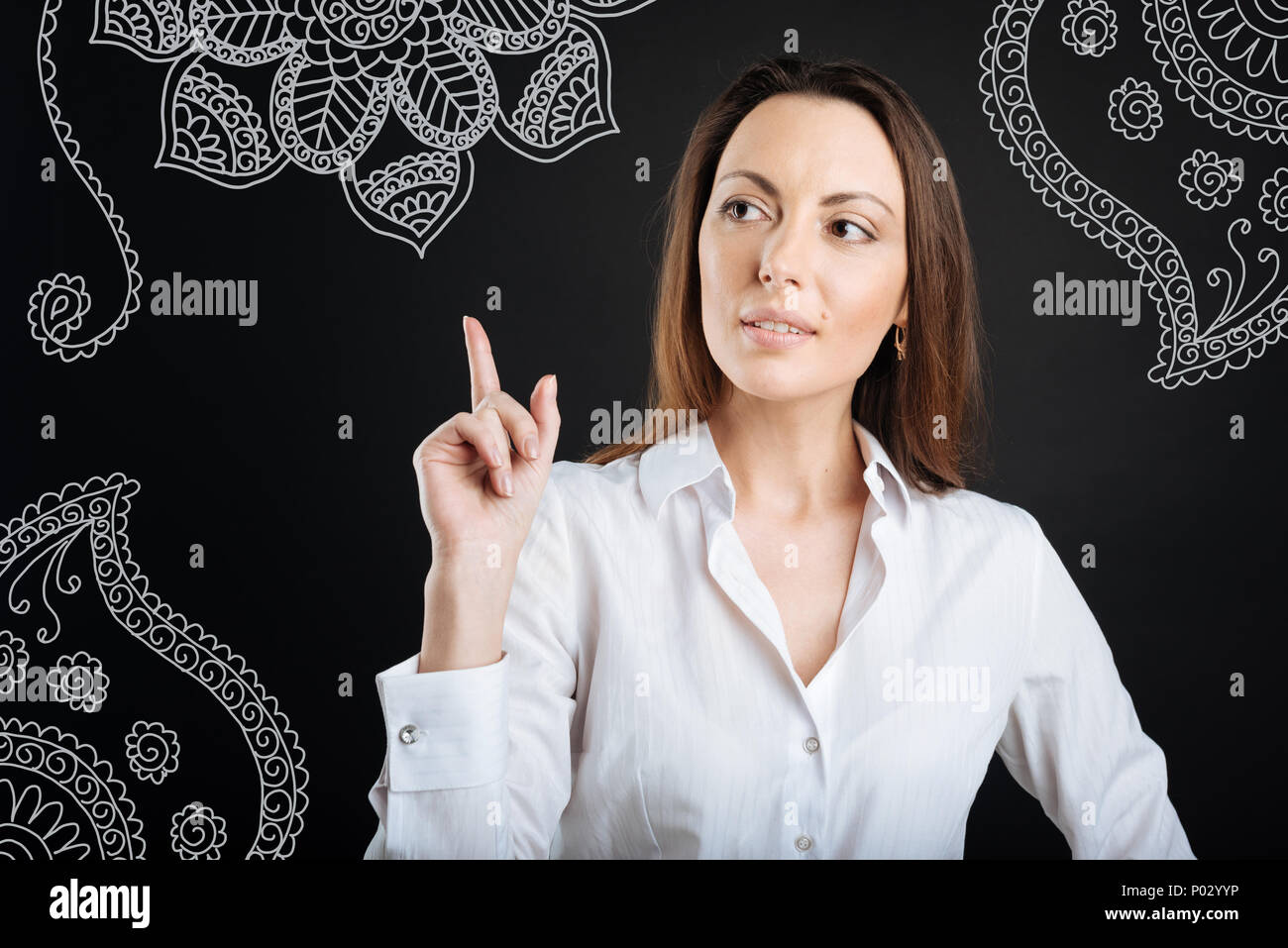 Clever teacher pointing her finger up while getting a wonderful idea ...