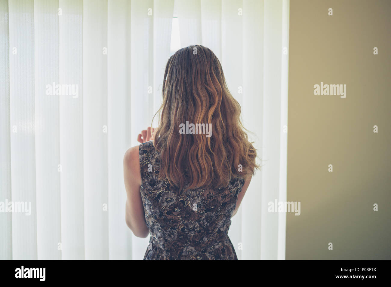 A young woman is peaking through the blinds at home Stock Photo - Alamy