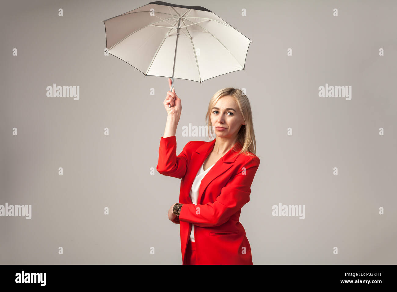 Young beautiful white blond girl in a bright red strict suit with a ...
