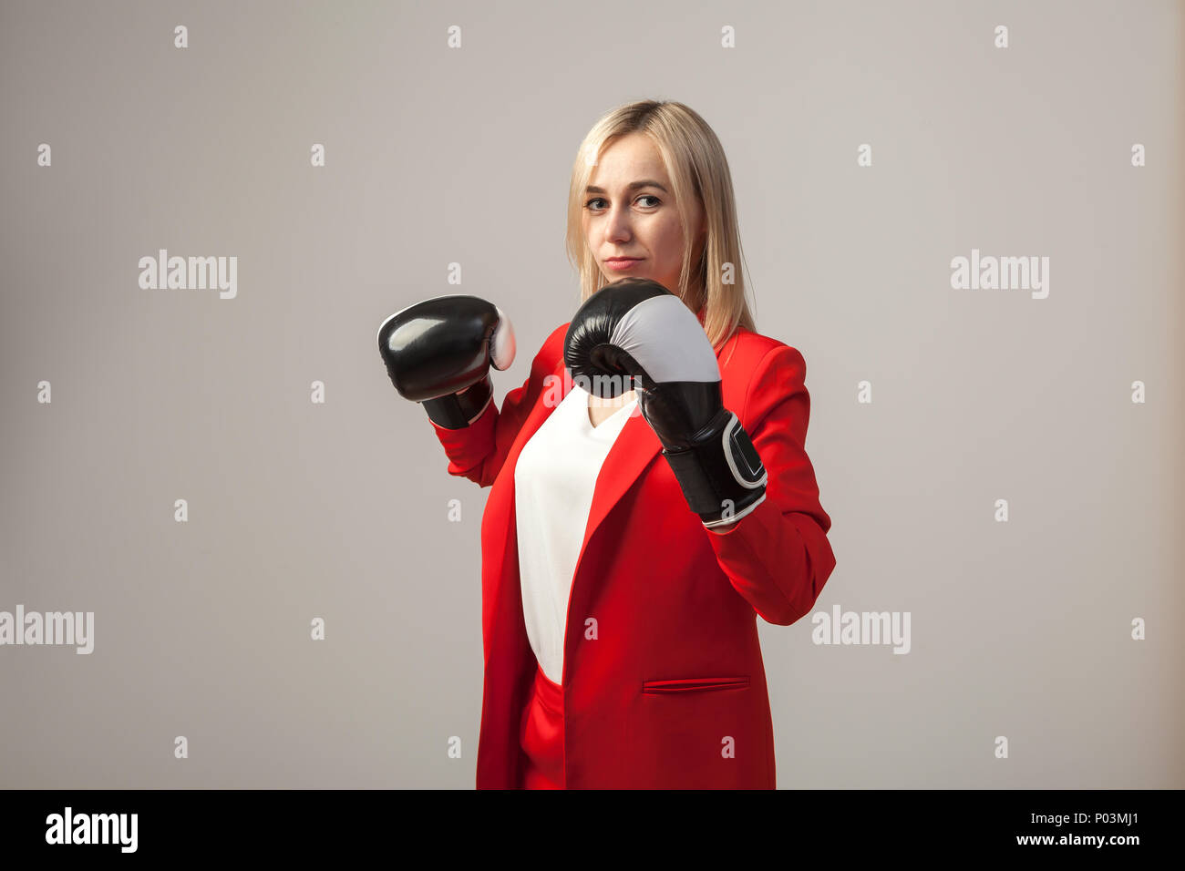 Young beautiful white blond girl in a bright red strict suit with a ...