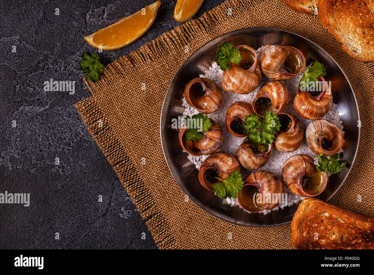 Fried snails with lemon, baguette and parsley, top view Stock Photo - Alamy