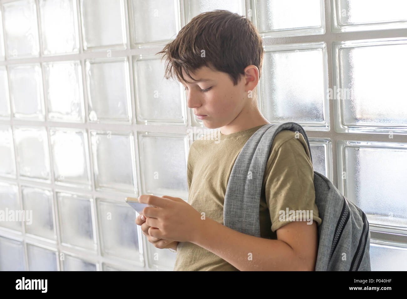 Student resting on the corridor of a school and playing with a mobile ...