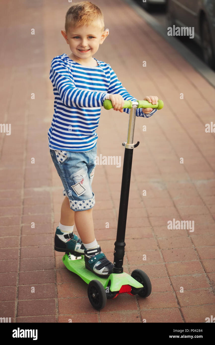little happy boy riding on scooter Stock Photo - Alamy