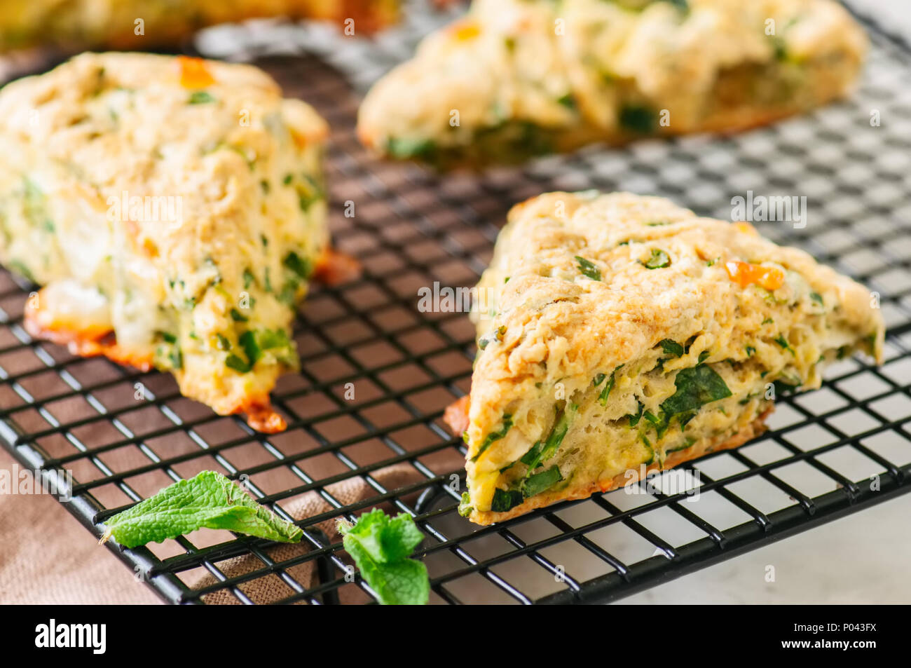Savory scones with feta mozarella and green herbs on a wire rack. White ...