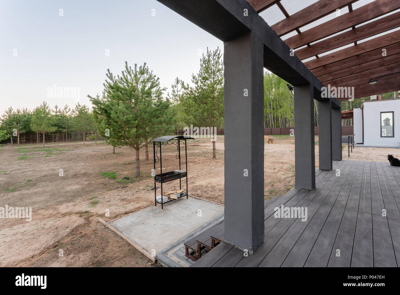 Side view of an open veranda in front of a modern forest cottage. Pine ...