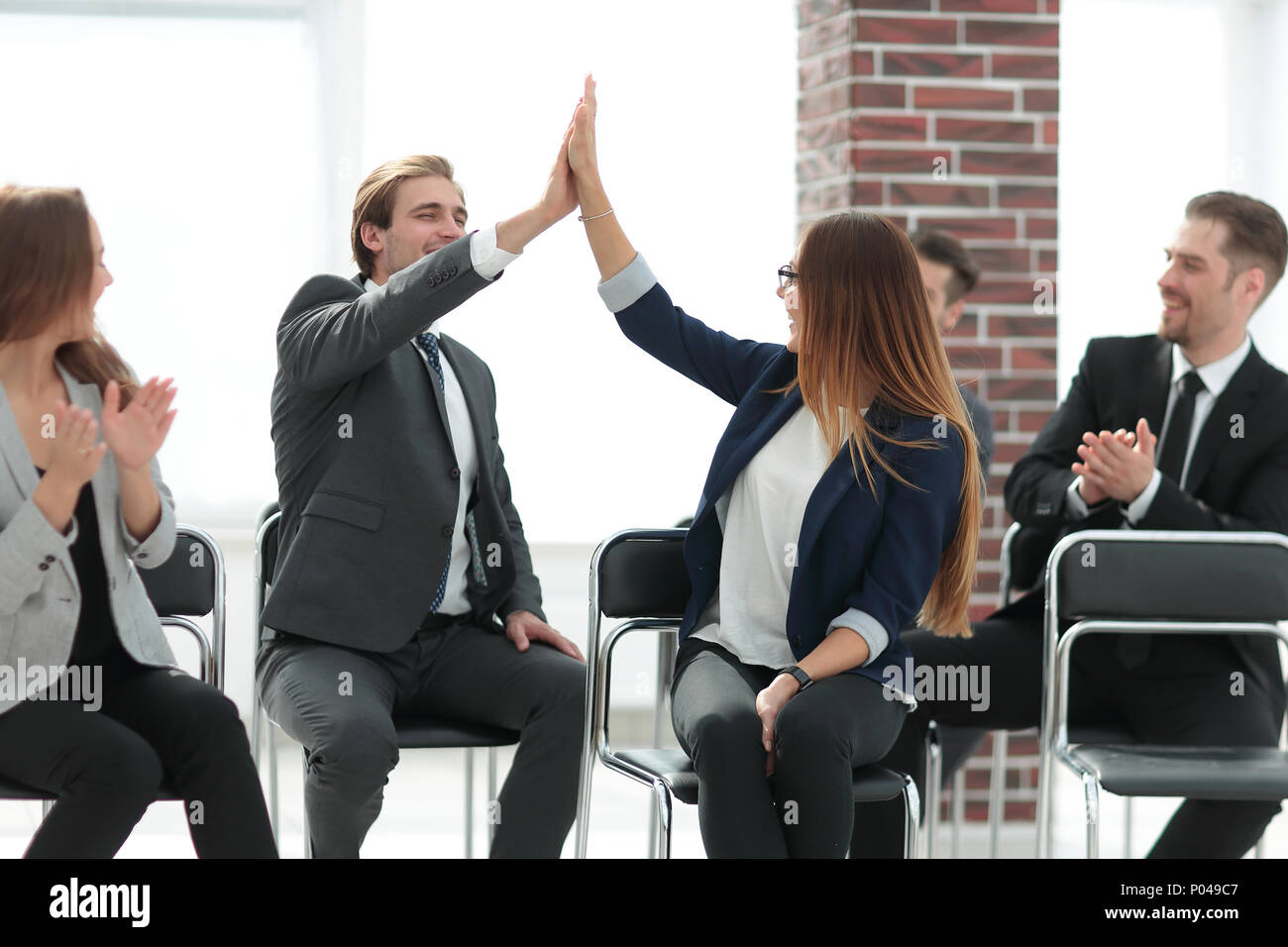 Happy colleagues giving high five at office Stock Photo - Alamy