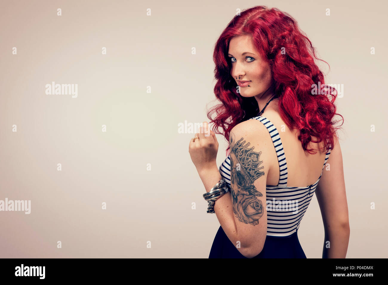 young woman with red hair and tattoos looking into the camera Stock ...
