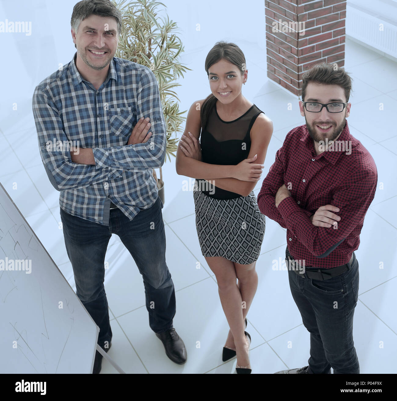 three optimistic office workers smiling in the camera from the top ...