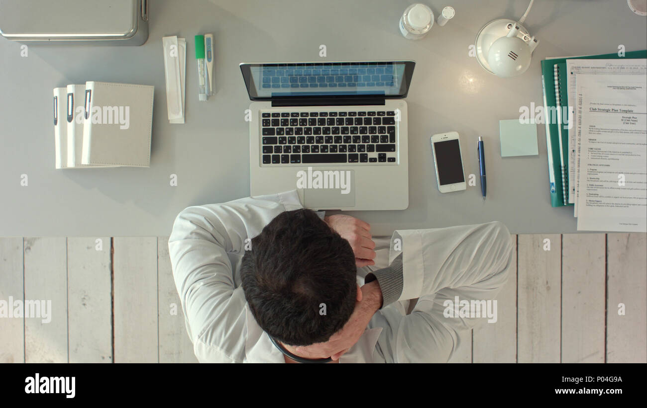 Thinking doctor with laptop in medical office. Top view Stock Photo - Alamy