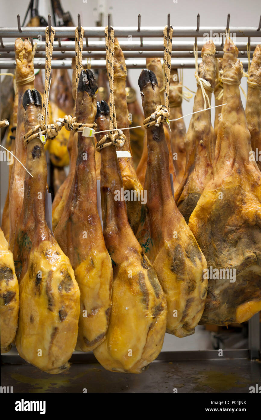 Iberian cured hums hanged in the market Stock Photo - Alamy