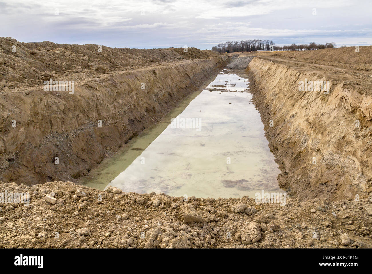 construction site including a big trench with lots of earth and loam ...