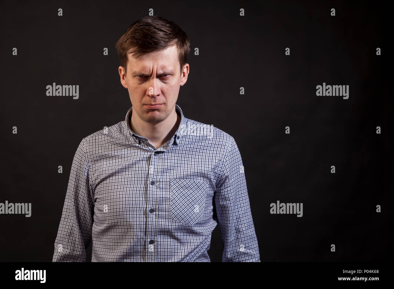 A dark haired white man with distrust expression face knit the brows in ...