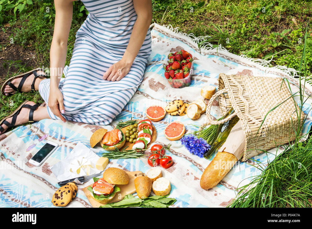 Picnic setting on the grass with basket, sandwiches, fruit, strawberry ...