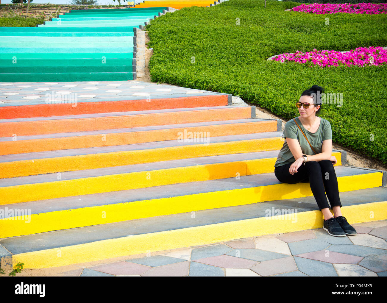 young woman sitting relaxed on bottom step of a concrete staircase ...
