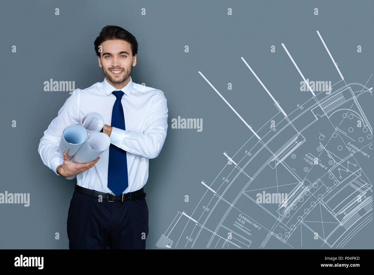 Confident engineer holding blueprints and smiling Stock Photo - Alamy
