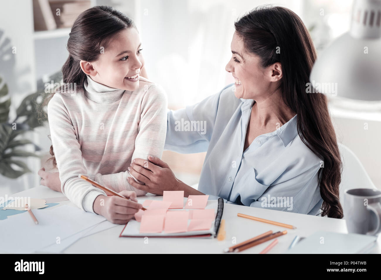 Positive delighted girl completing task with her mother Stock Photo - Alamy