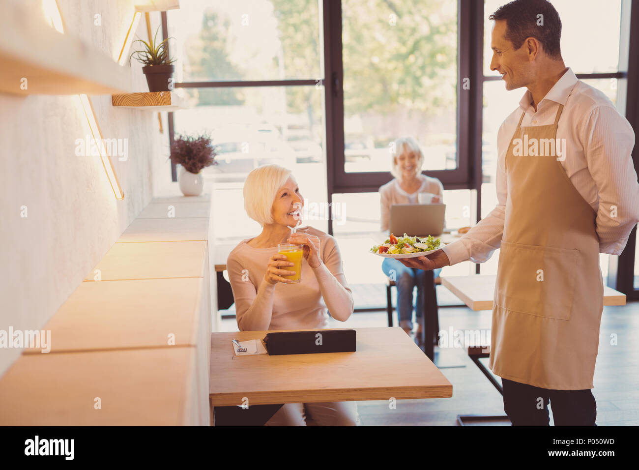 Quick service. Charming well-built young waiter serving a salad to his ...