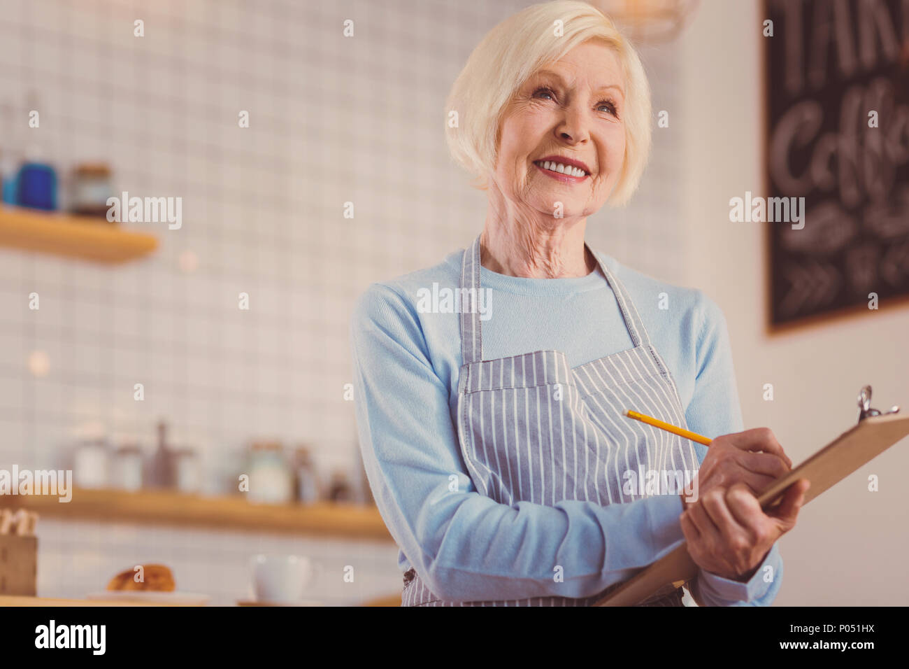 Upbeat senior waitress taking notes about clients order Stock Photo - Alamy