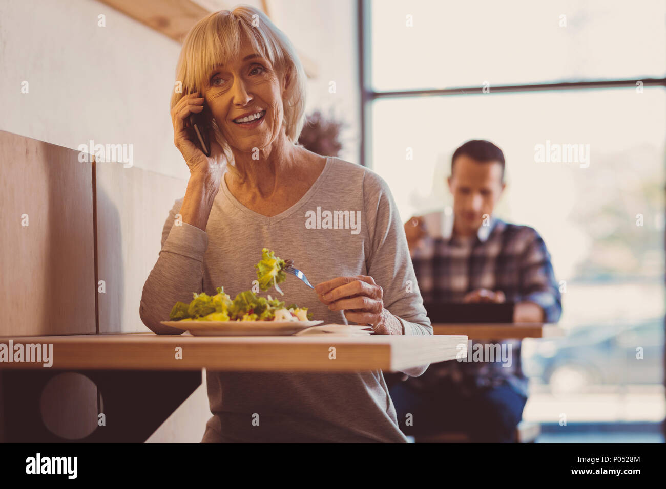 Upbeat woman making phone call while eating out Stock Photo - Alamy