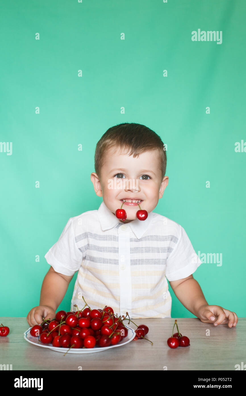 A little boy eating ripe cherries. Little Boy On A Green Background ...