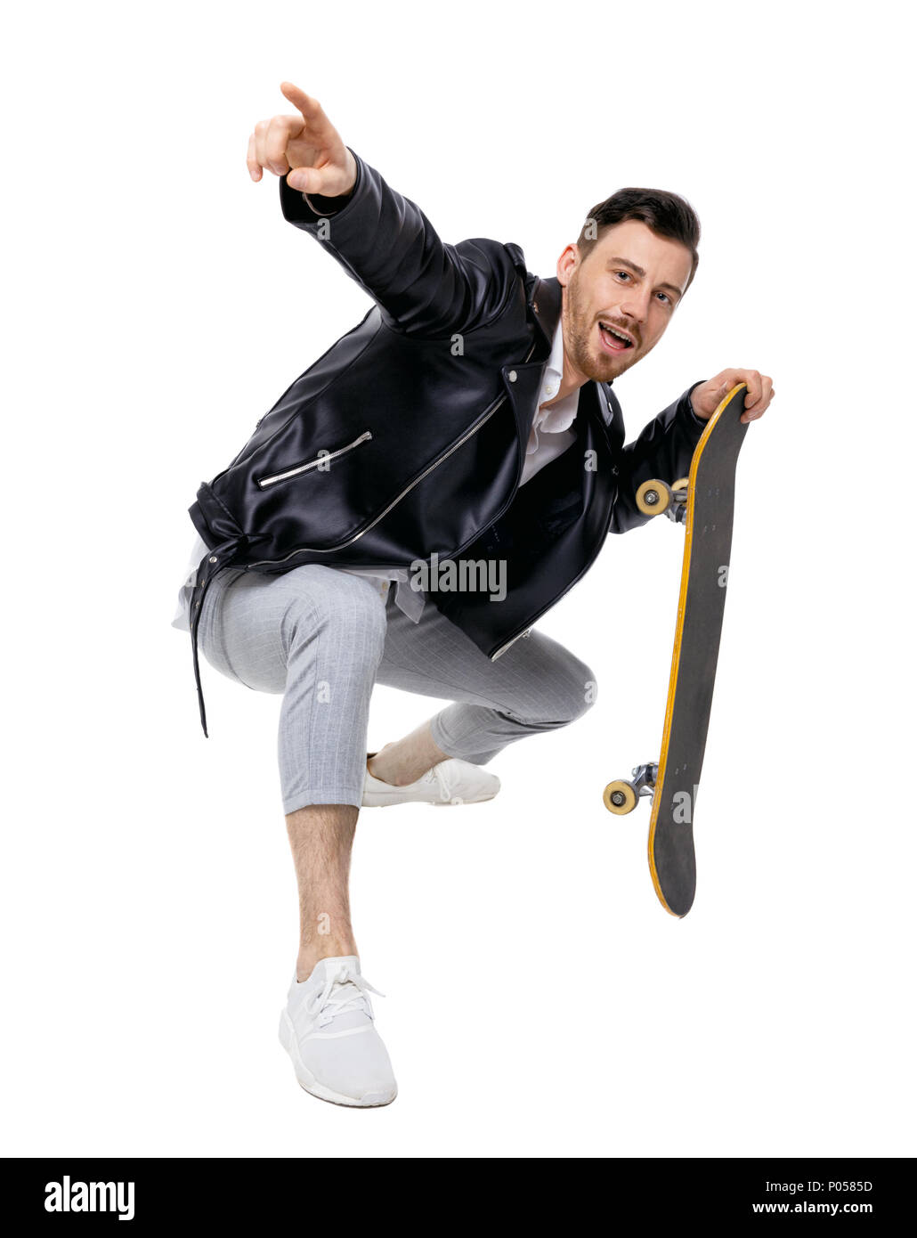 A man with a skateboard. A guy in stylish clothes and trousers posing ...