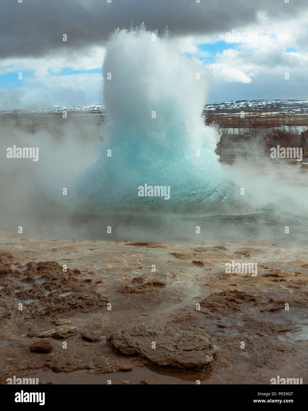 Iceland, The great geyser exploding with distant snow covered mountains ...