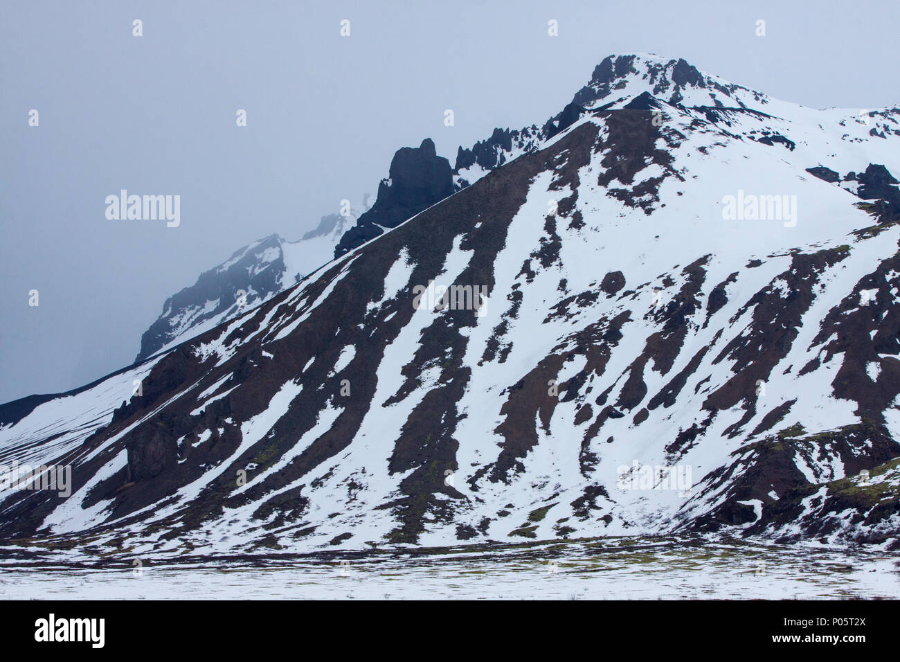 Icelandic mountain with black rocks showing through the melting snow ...