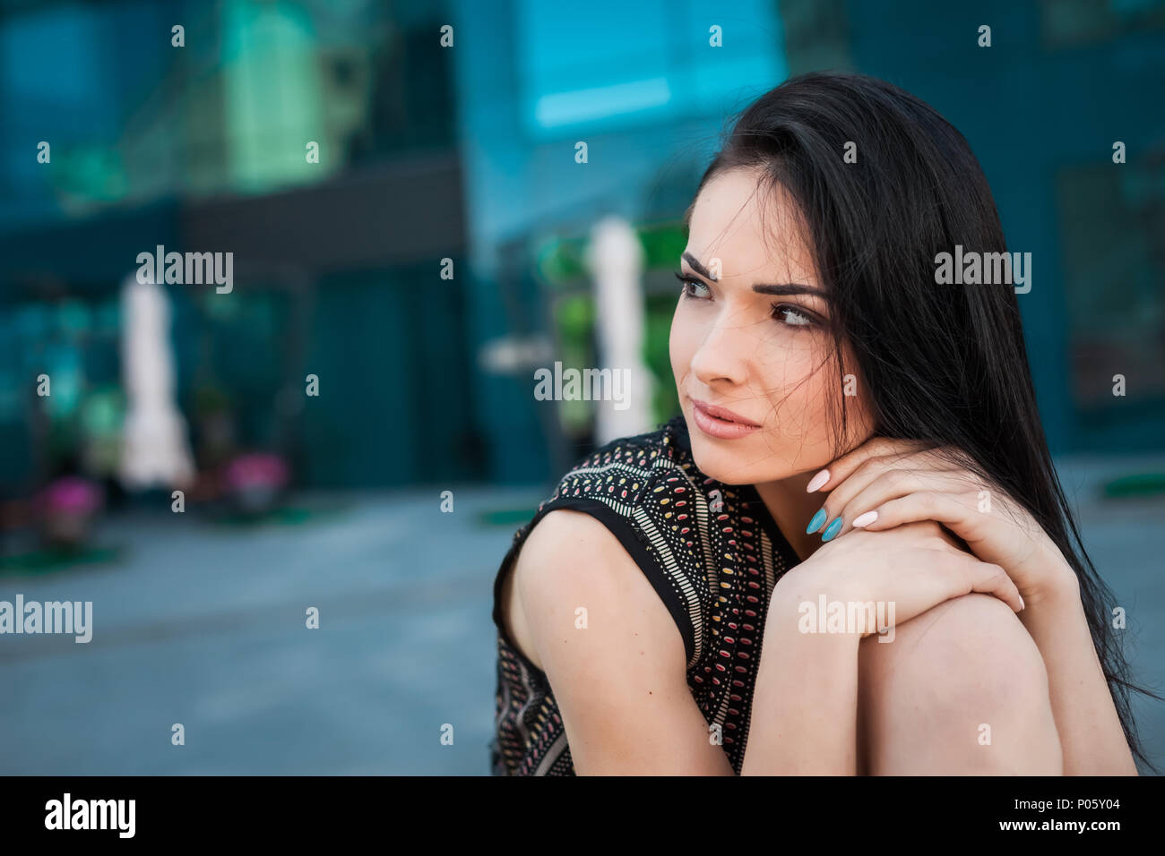 beautiful thoughtfull brunette girl sitting on the curb Stock Photo - Alamy