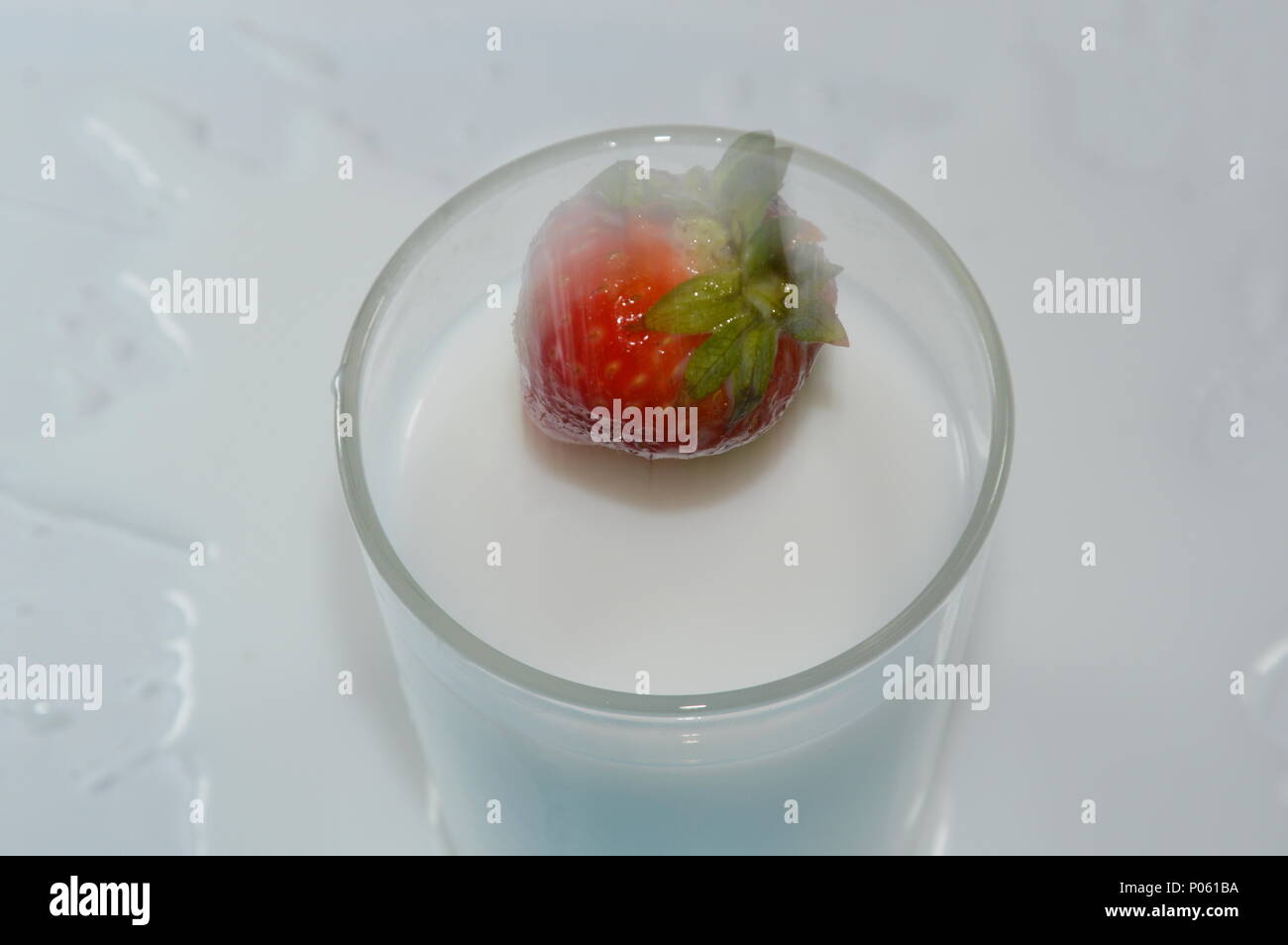 strawberry drop on milk glass Stock Photo - Alamy