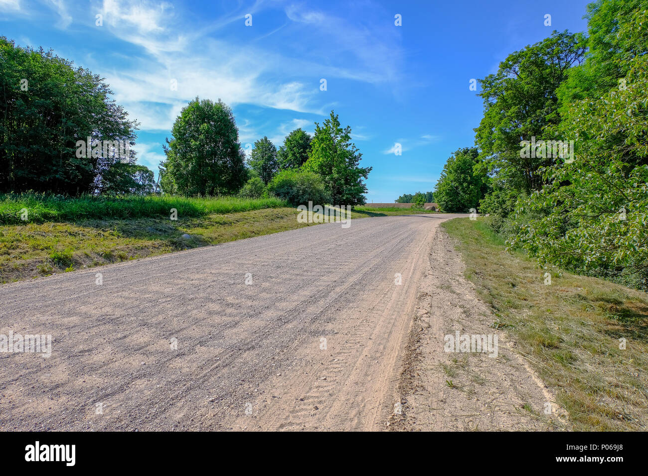 empty gravel road with tracks of mud in the countryside in summer heat ...