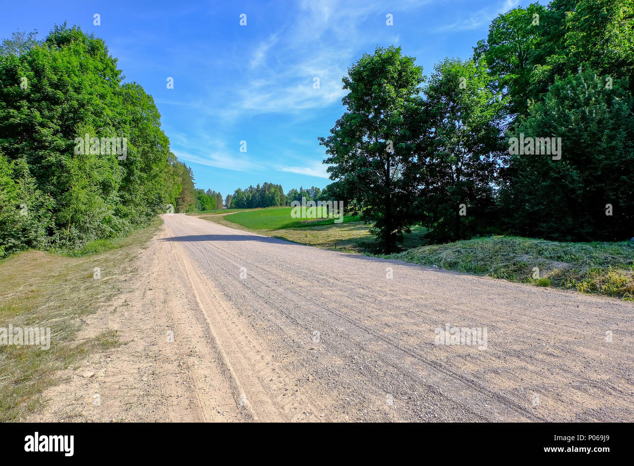 empty gravel road with tracks of mud in the countryside in summer heat ...