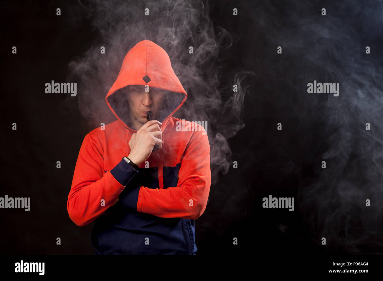 A young dark-haired man in a colored orange and blue hoody standing in ...