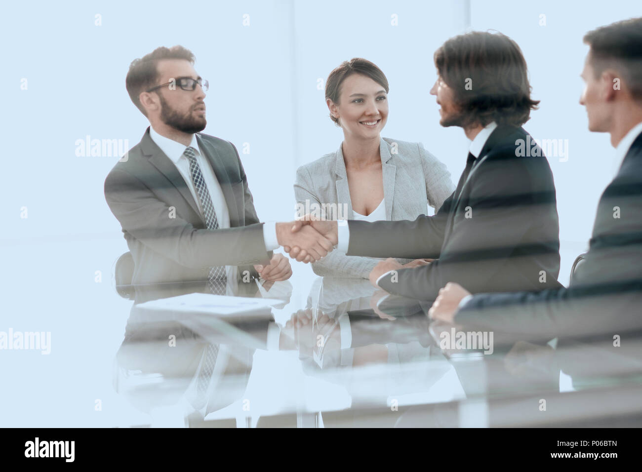 from behind the glass.handshake of business partners in the office ...