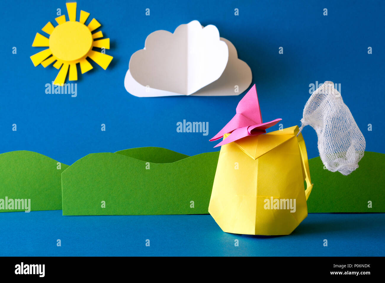 Paper backpack with butterfly net on grass field at blue background ...