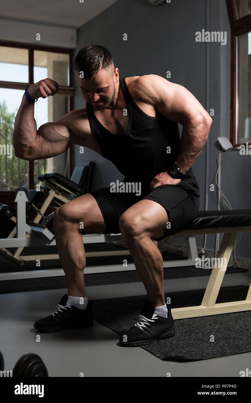 Healthy Young Man Sitting Strong In The Gym And Flexing Muscles ...