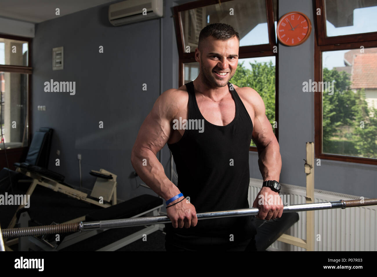 Muscular Man Doing Heavy Weight Exercise For Forearm With Barbell In ...