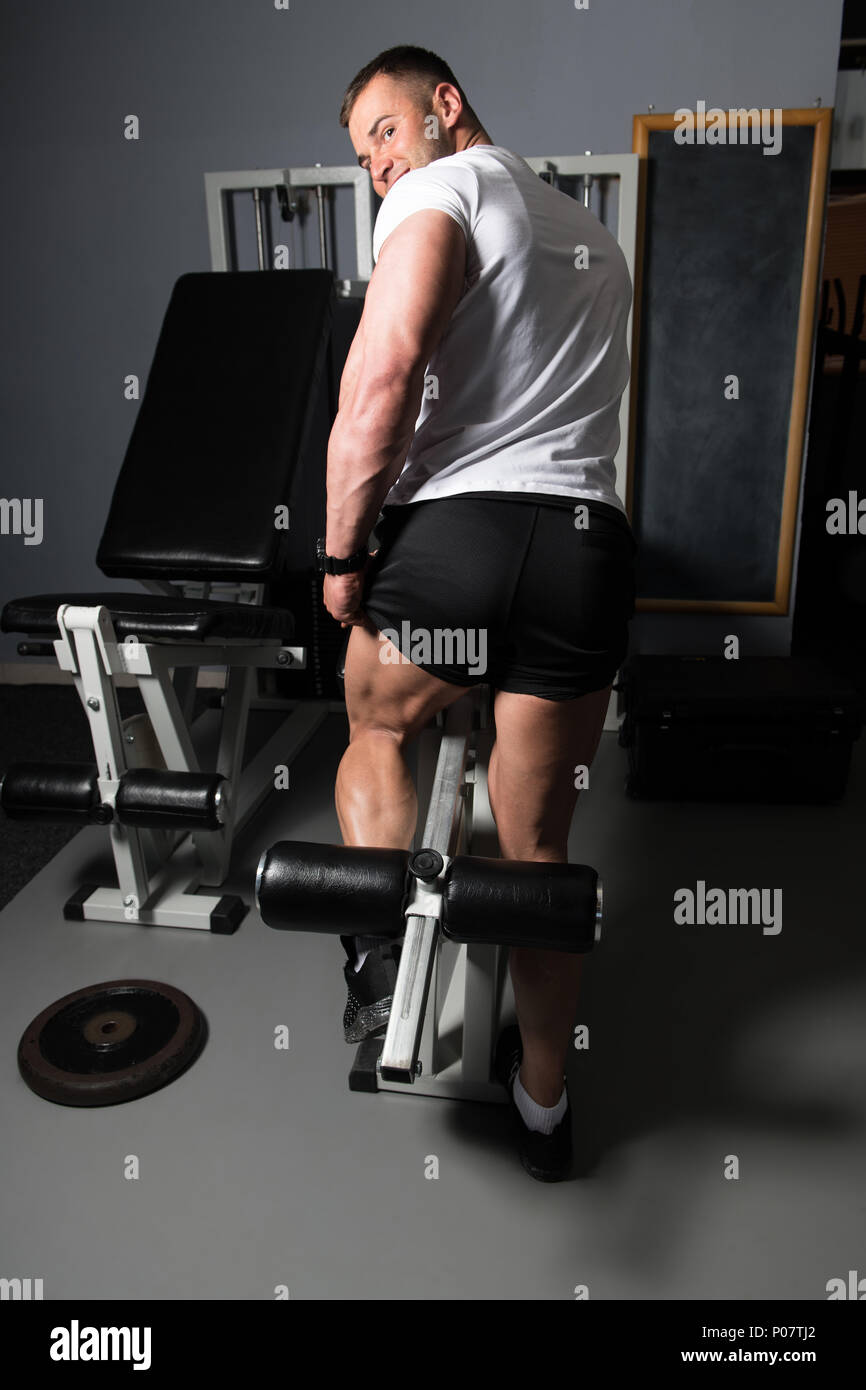 Strong Man In The Gym And Exercising Quadriceps And Glutes On Machine ...