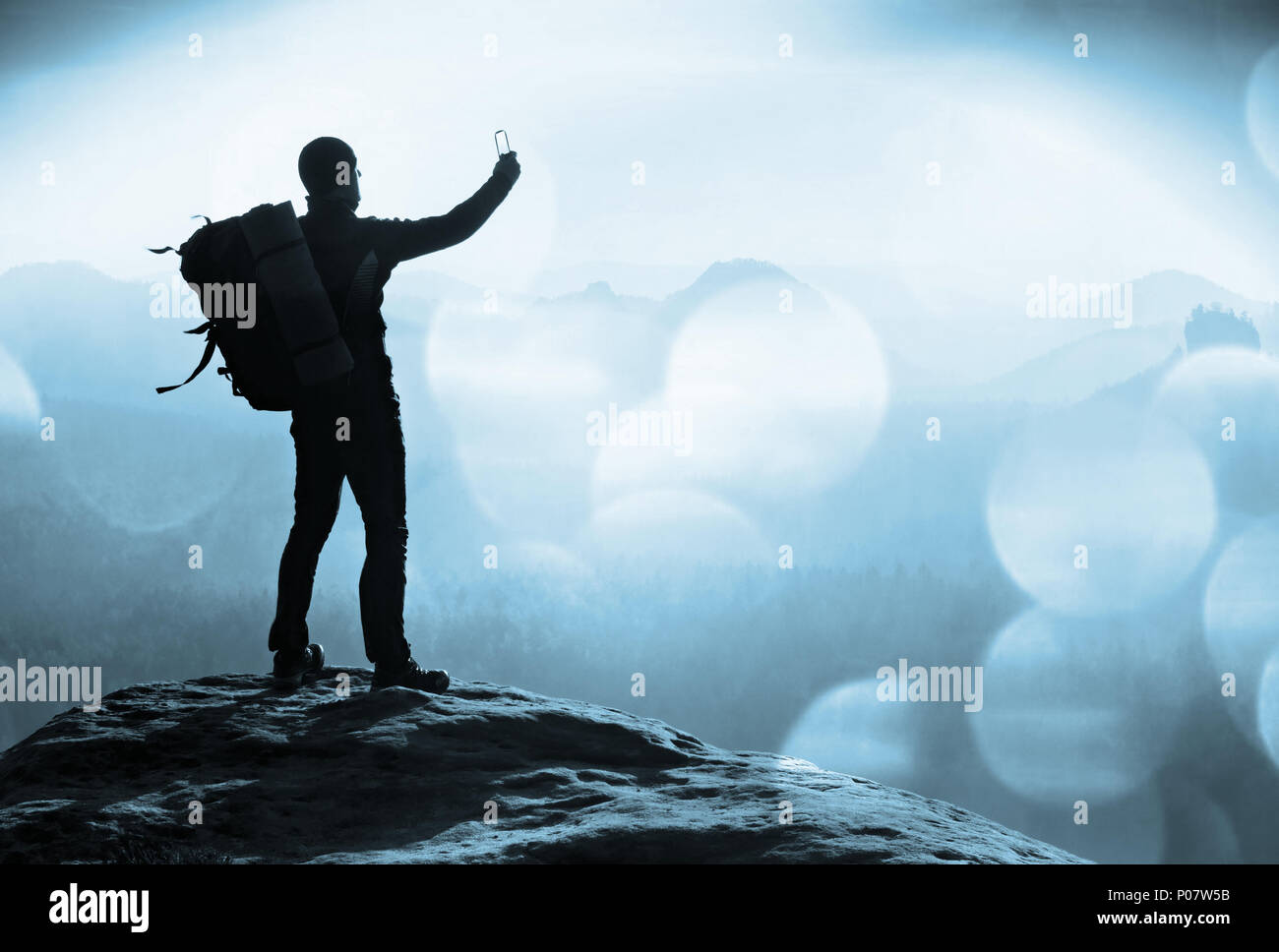 Flare, soft focus. Man shadowing eyes. Alone tourist on cliff edge and ...