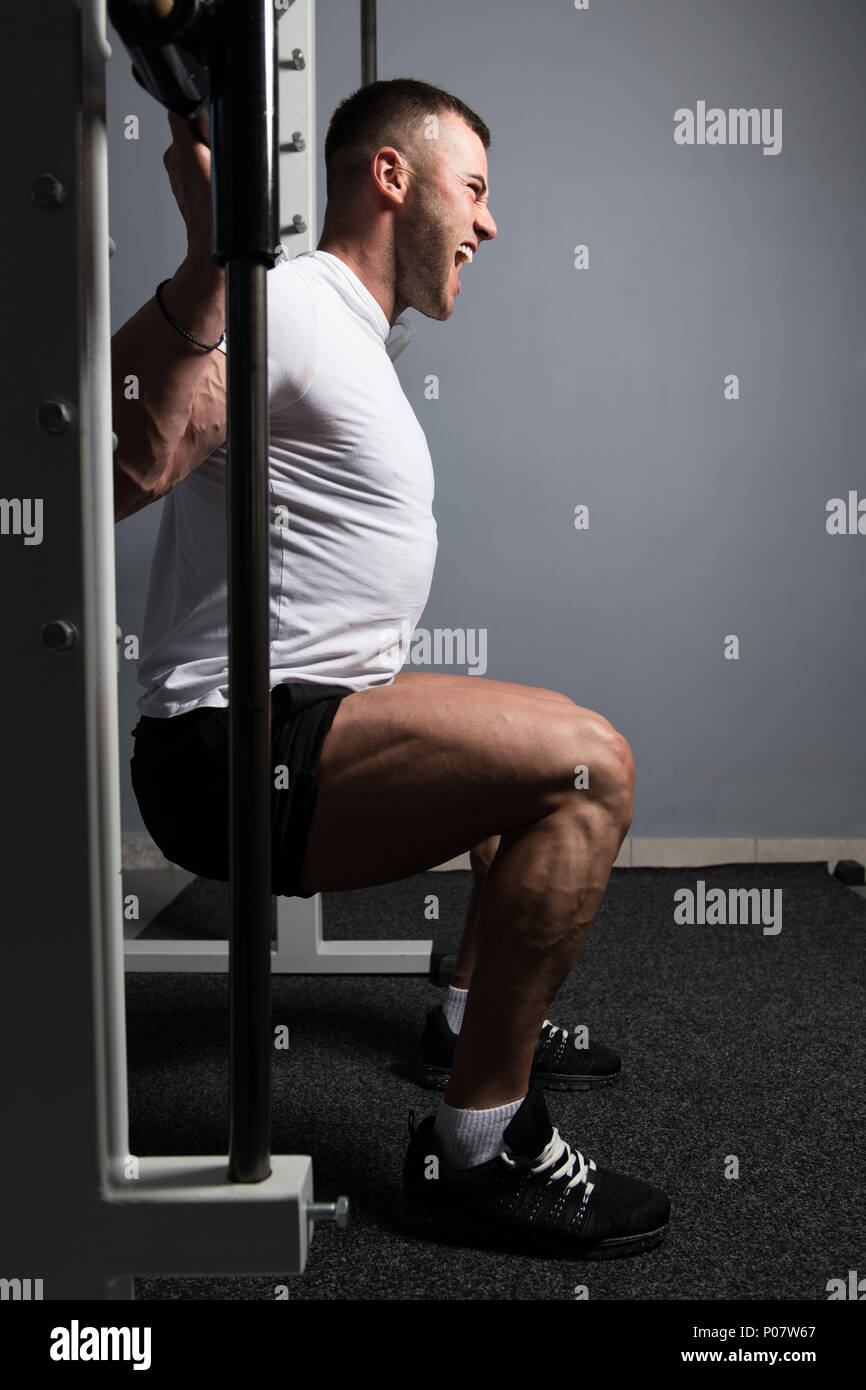 Healthy Fitness Man Working Out Legs With Barbell In A Gym - Squat ...