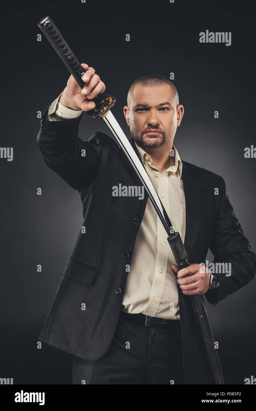 man in suit taking of his katana sword on black Stock Photo - Alamy