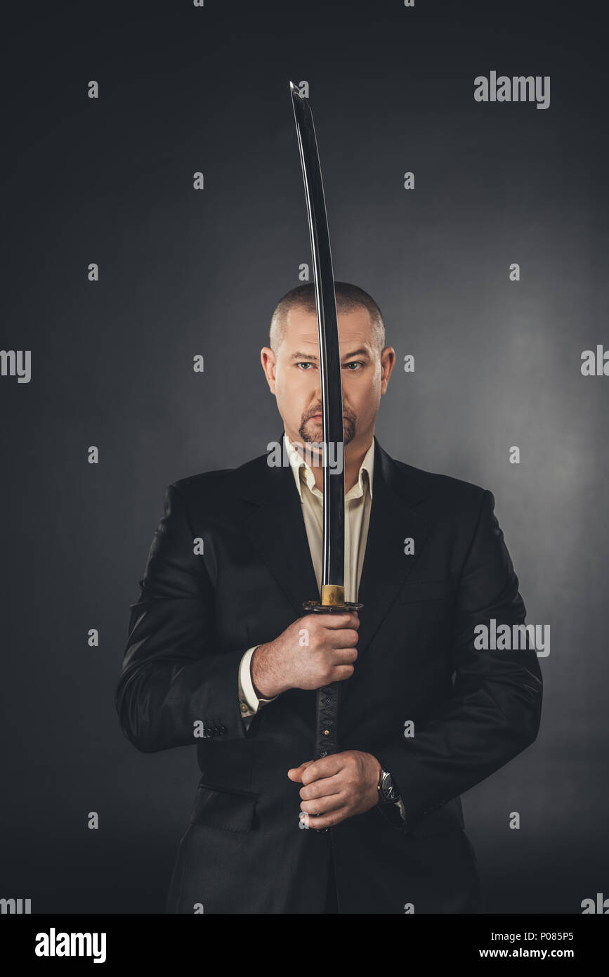 man in suit holding katana sword in front of his face on black Stock ...