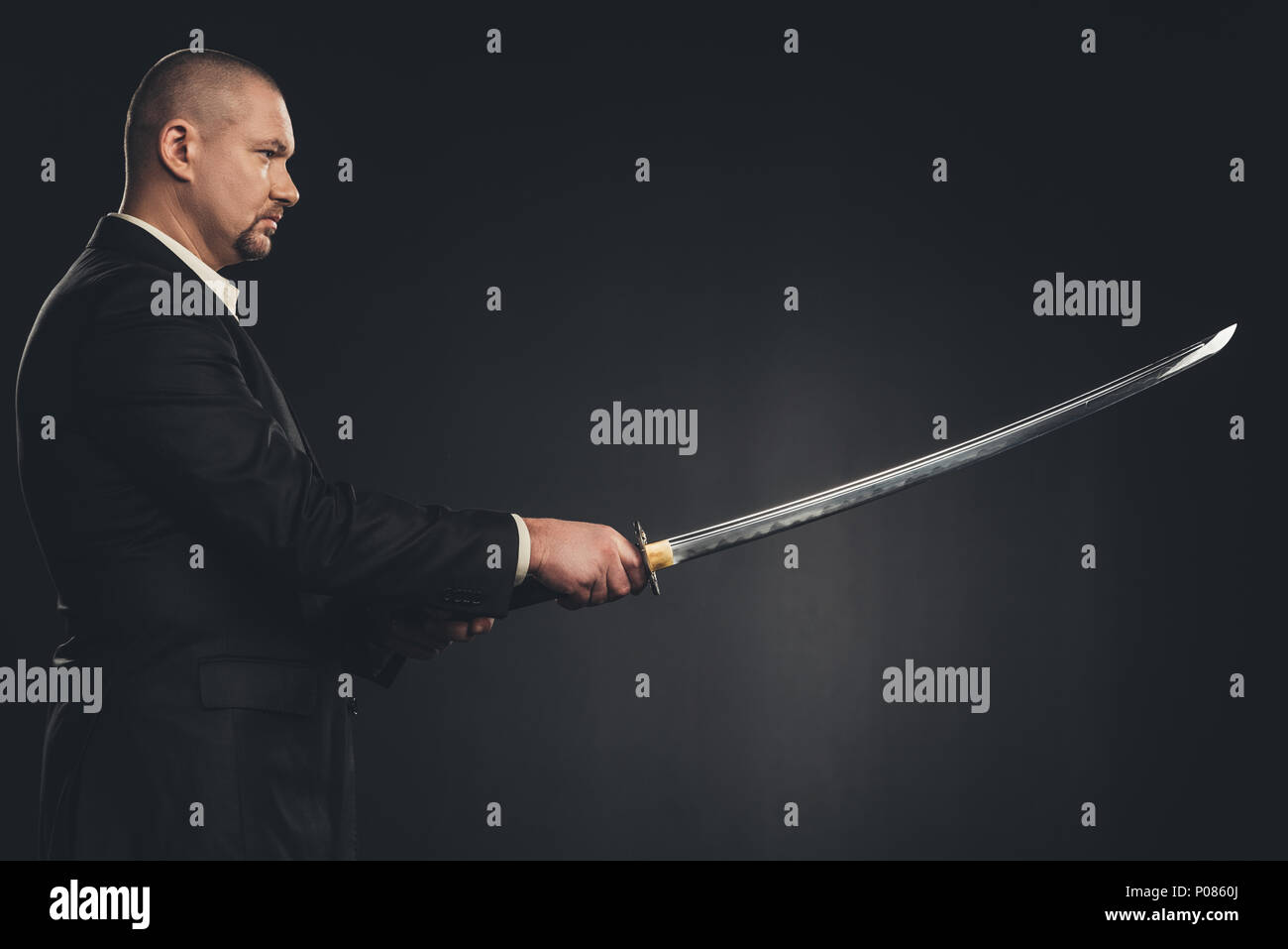 side view of man in suit with katana sword isolated on black Stock ...