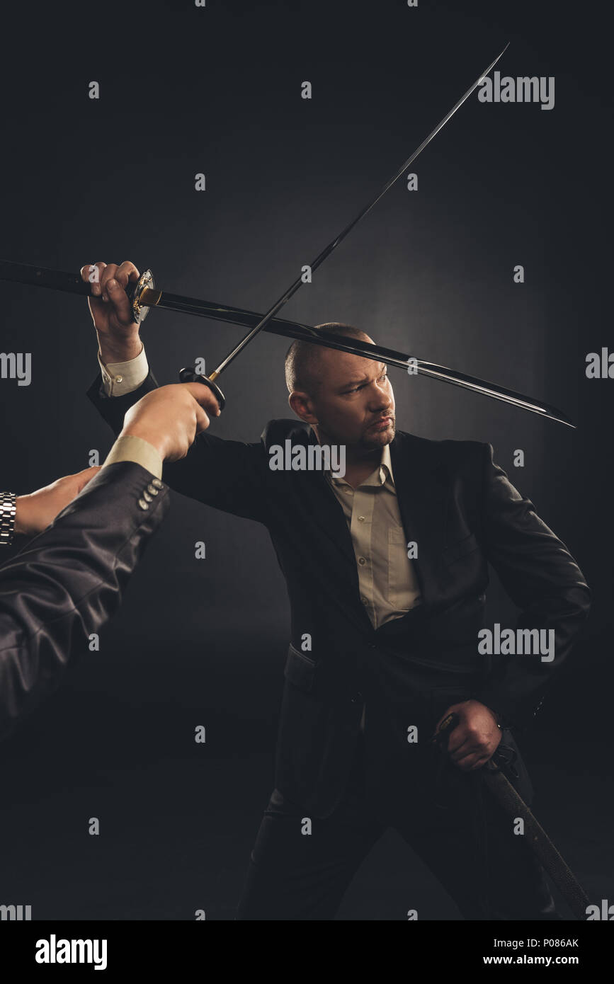 strong mature businessman fighting with katana sword isolated on black ...