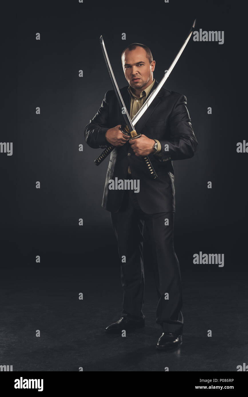 handsome man in suit with dual katana swords on black Stock Photo - Alamy
