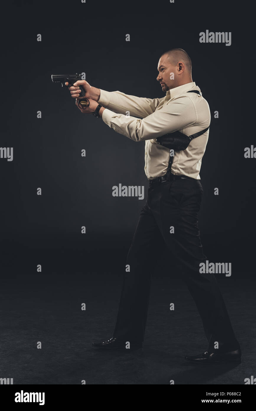side view of security man holding gun on black Stock Photo - Alamy