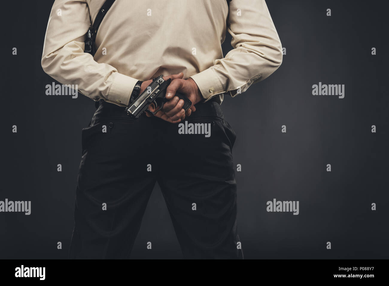 back view of man in shirt holding gun behind back Stock Photo - Alamy
