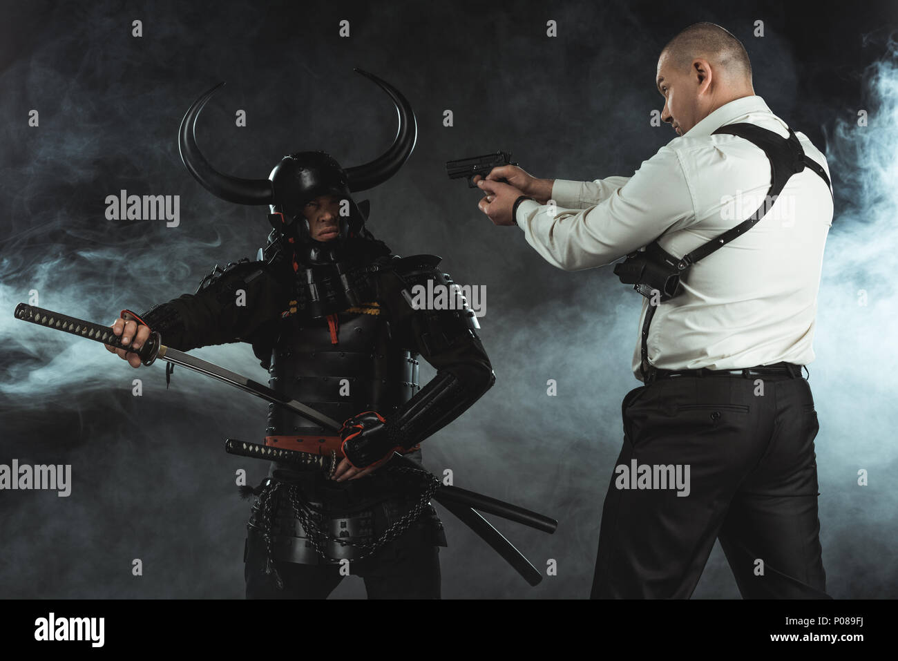 mature modern man aiming on samurai with gun while he taking out his ...