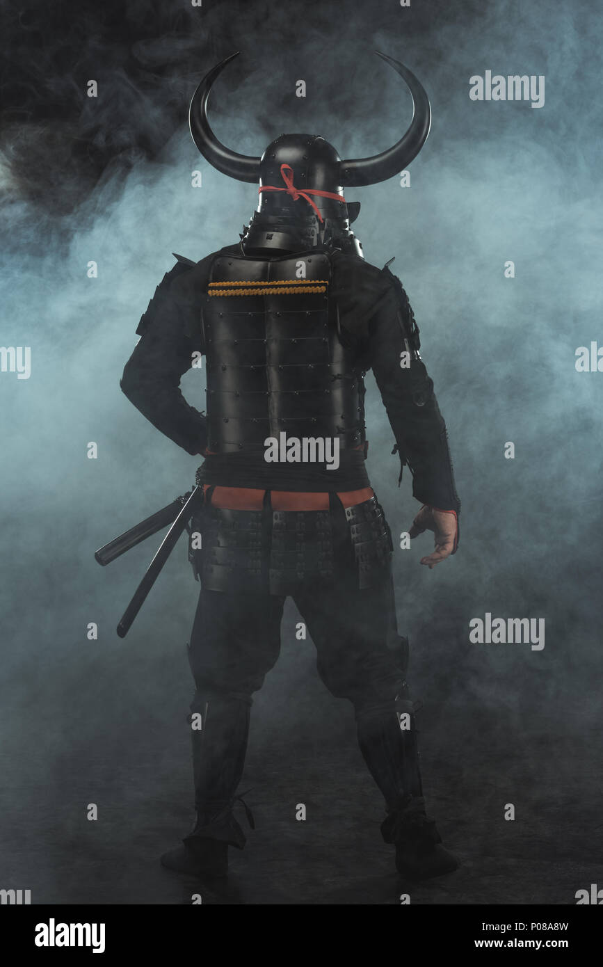 rear view of samurai in traditional armor on dark background with smoke ...