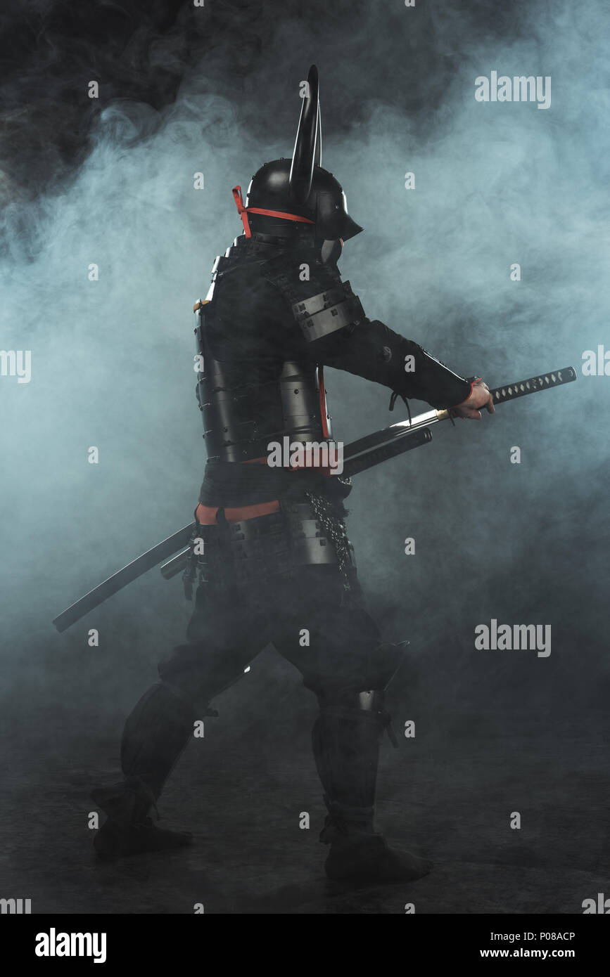 side view of samurai taking out his katana on dark background with ...